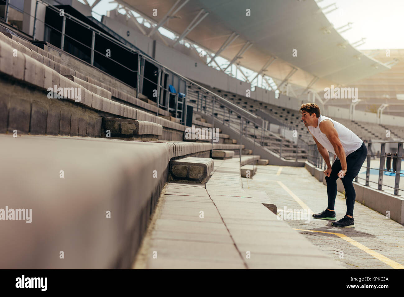 Athlete doing exercise in the stands of a track and field stadium ...