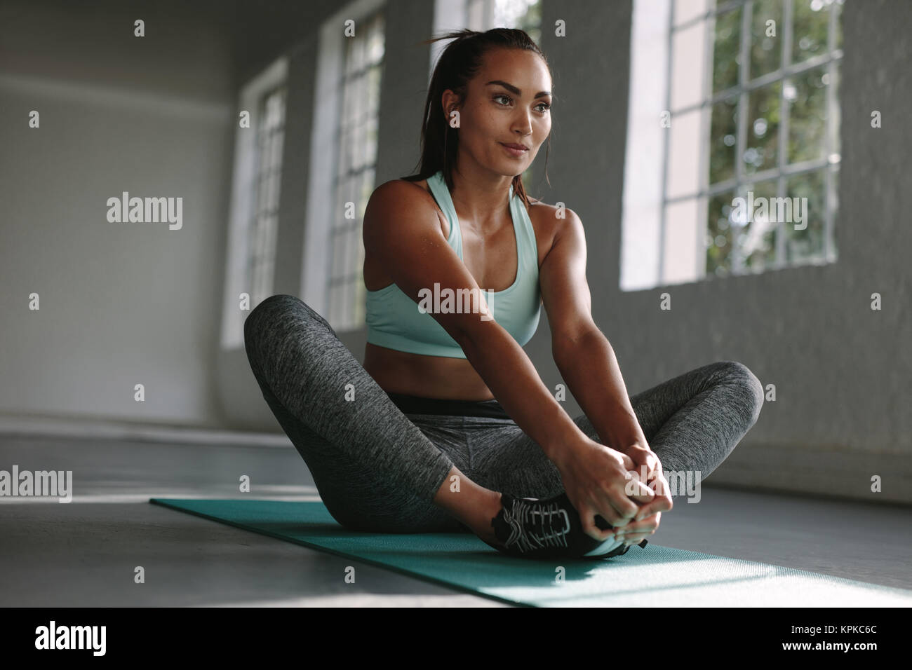 Woman doing stretches on exercise mat in gym. Baddha Konasana being ...