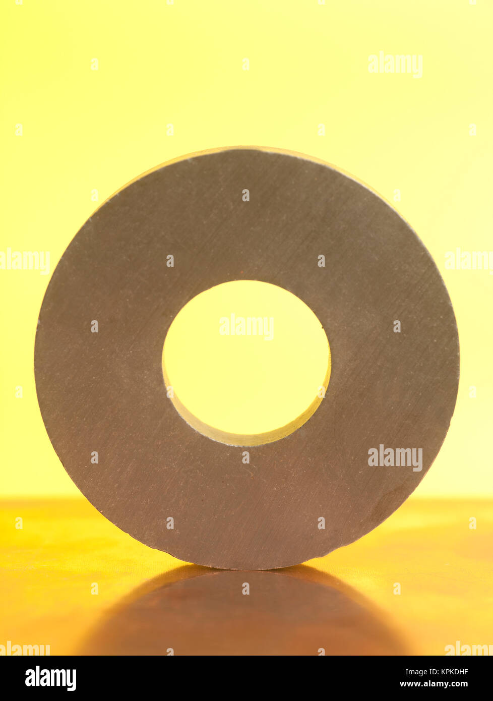 Round magnet on a yellow background Stock Photo - Alamy
