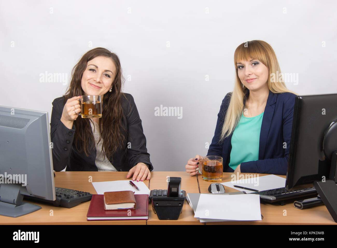 Two girls drink tea, office behind a desk Stock Photo - Alamy