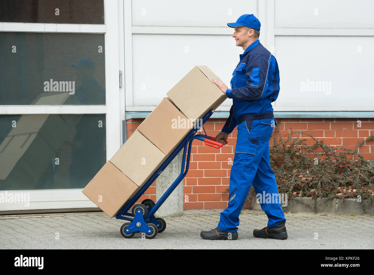 Delivery man carrying boxes on a hand truck hi-res stock photography ...