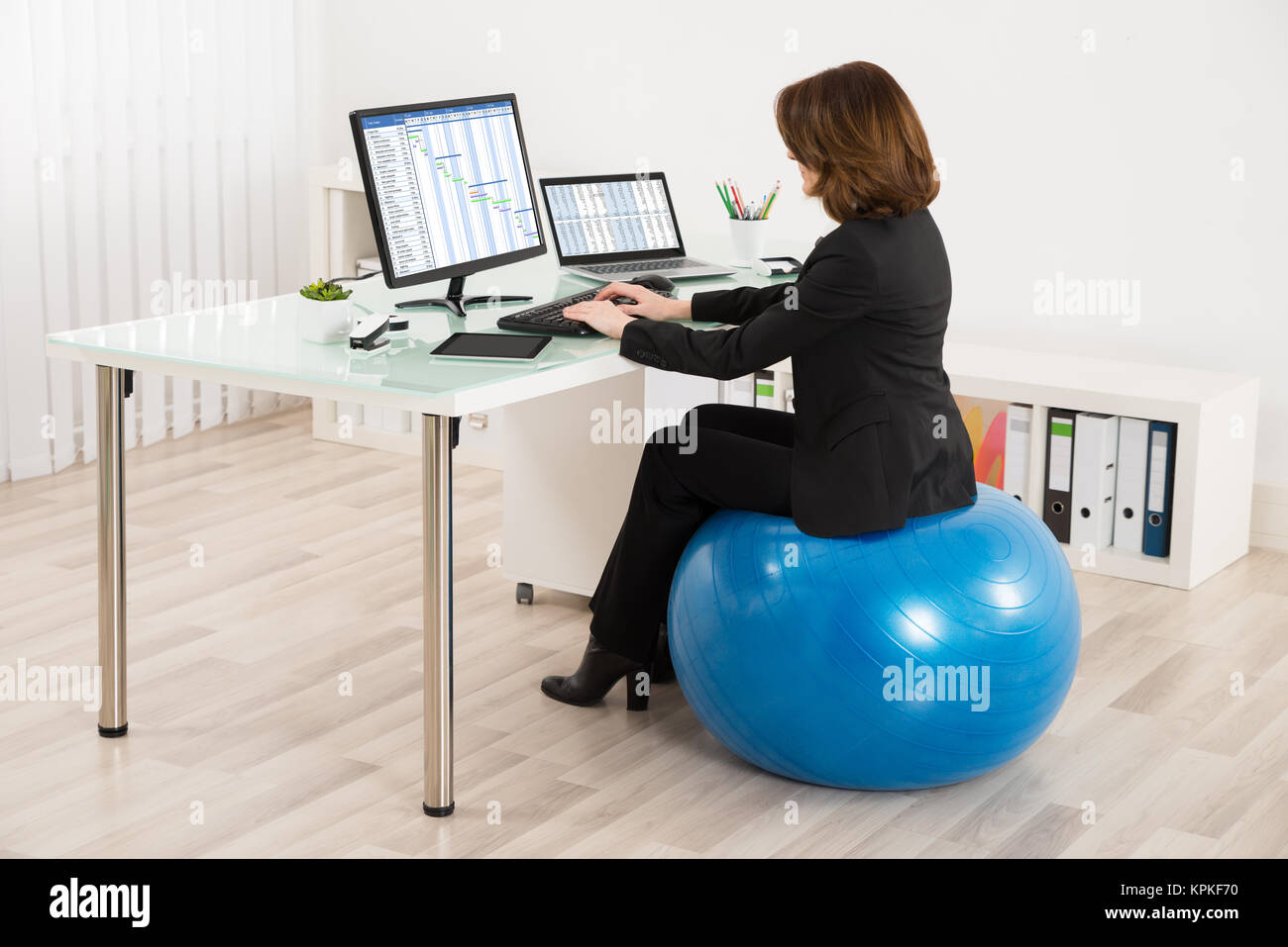 Businesswoman Sitting On Pilates Ball Working Stock Photo - Alamy