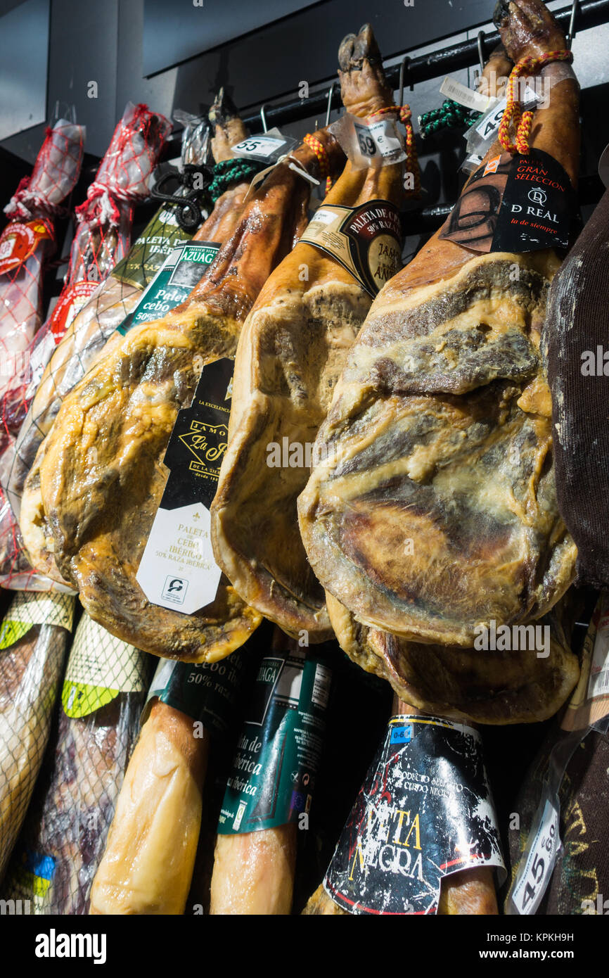 Whole cured Iberian ham hanging up in a Spanish supermarket Stock Photo ...