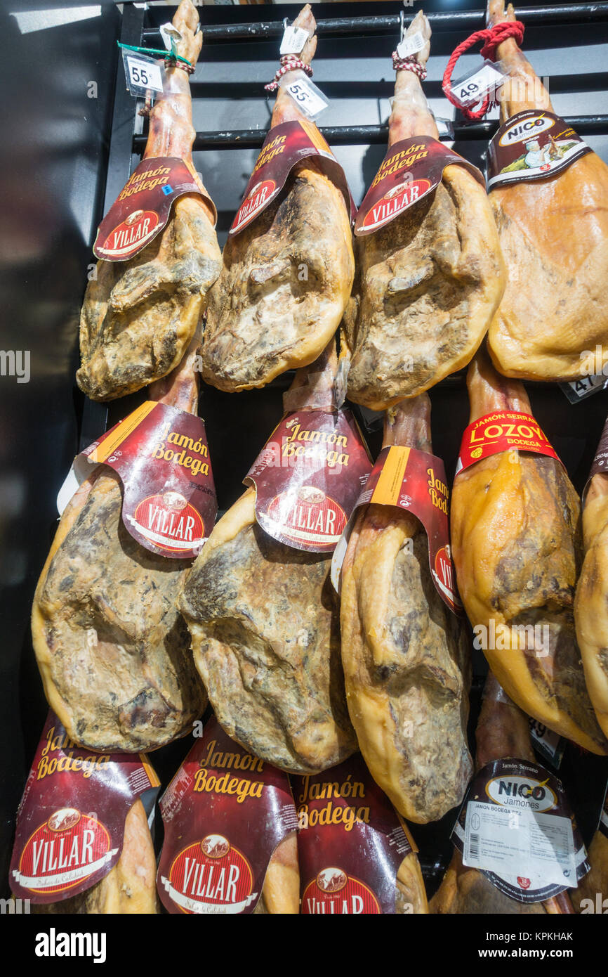 Whole cured Iberian ham hanging up in a Spanish supermarket Stock Photo ...