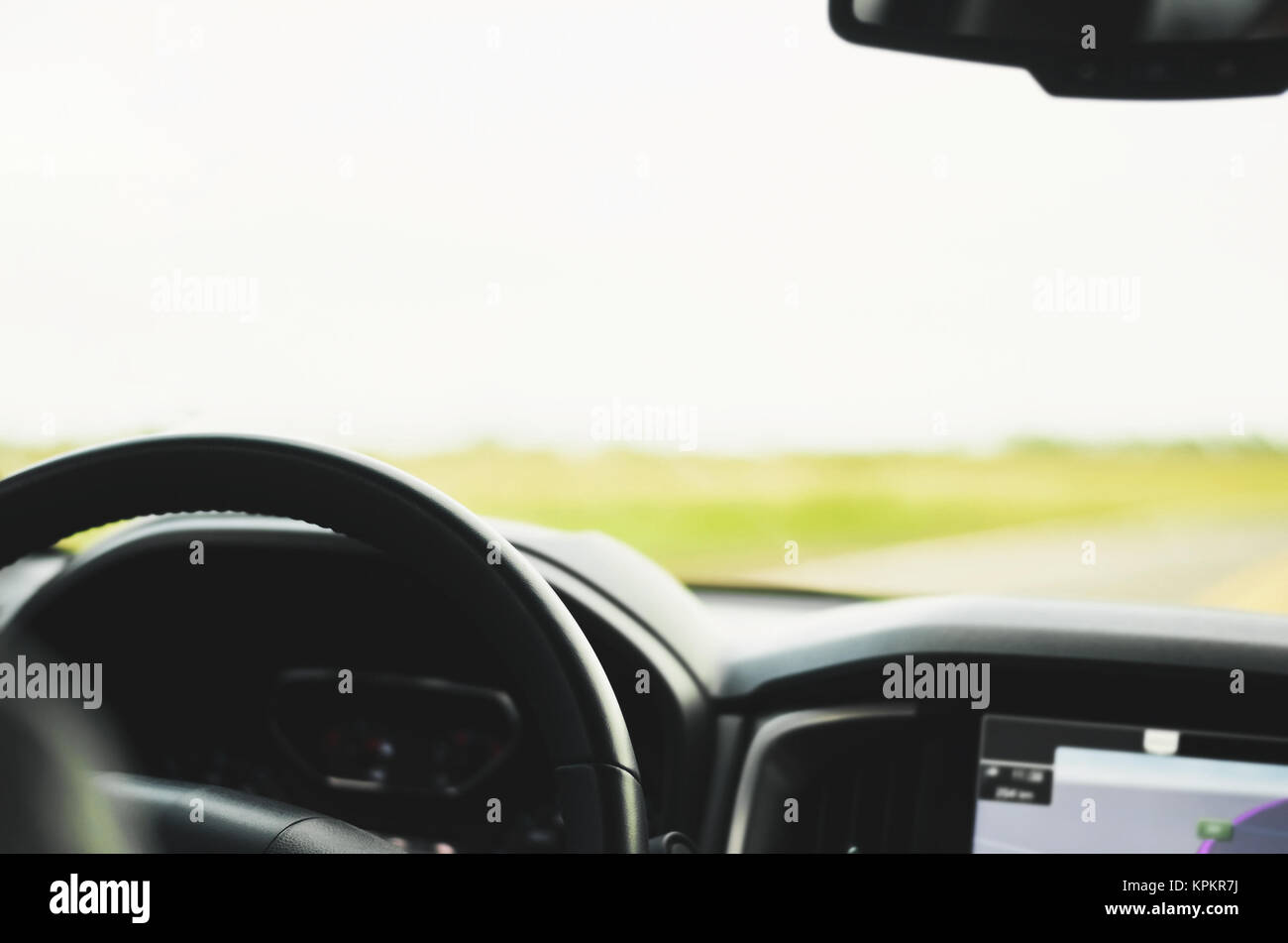 Car dashboard, focus on the wheel. Car in movement, landscape outside ...