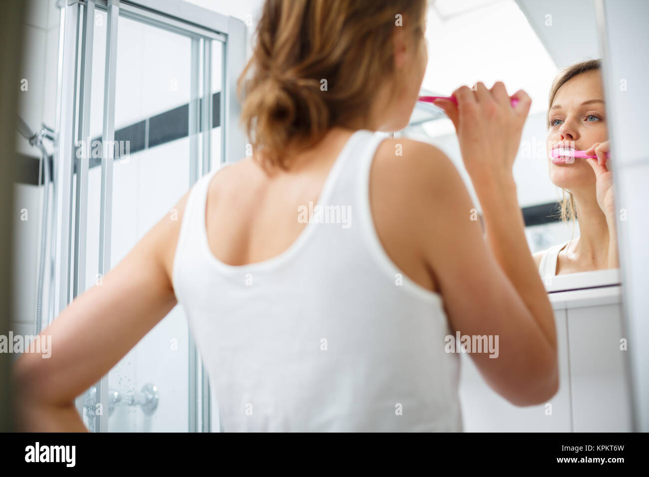 Pretty Female Brushing Her Teeth In Front Of Mirror In The Morning