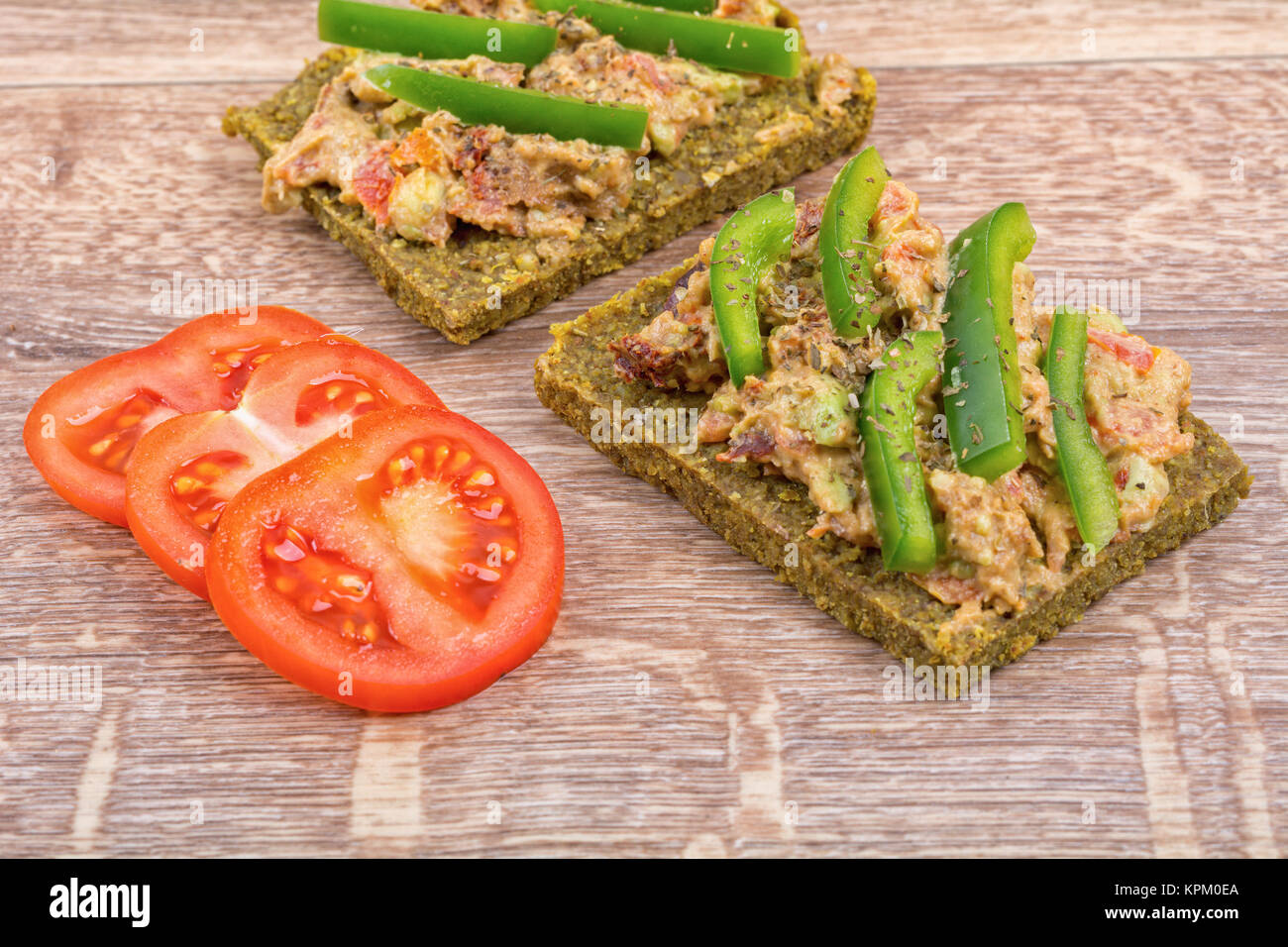Raw bread with a spread decorated with pepper and tomatoes Stock Photo ...