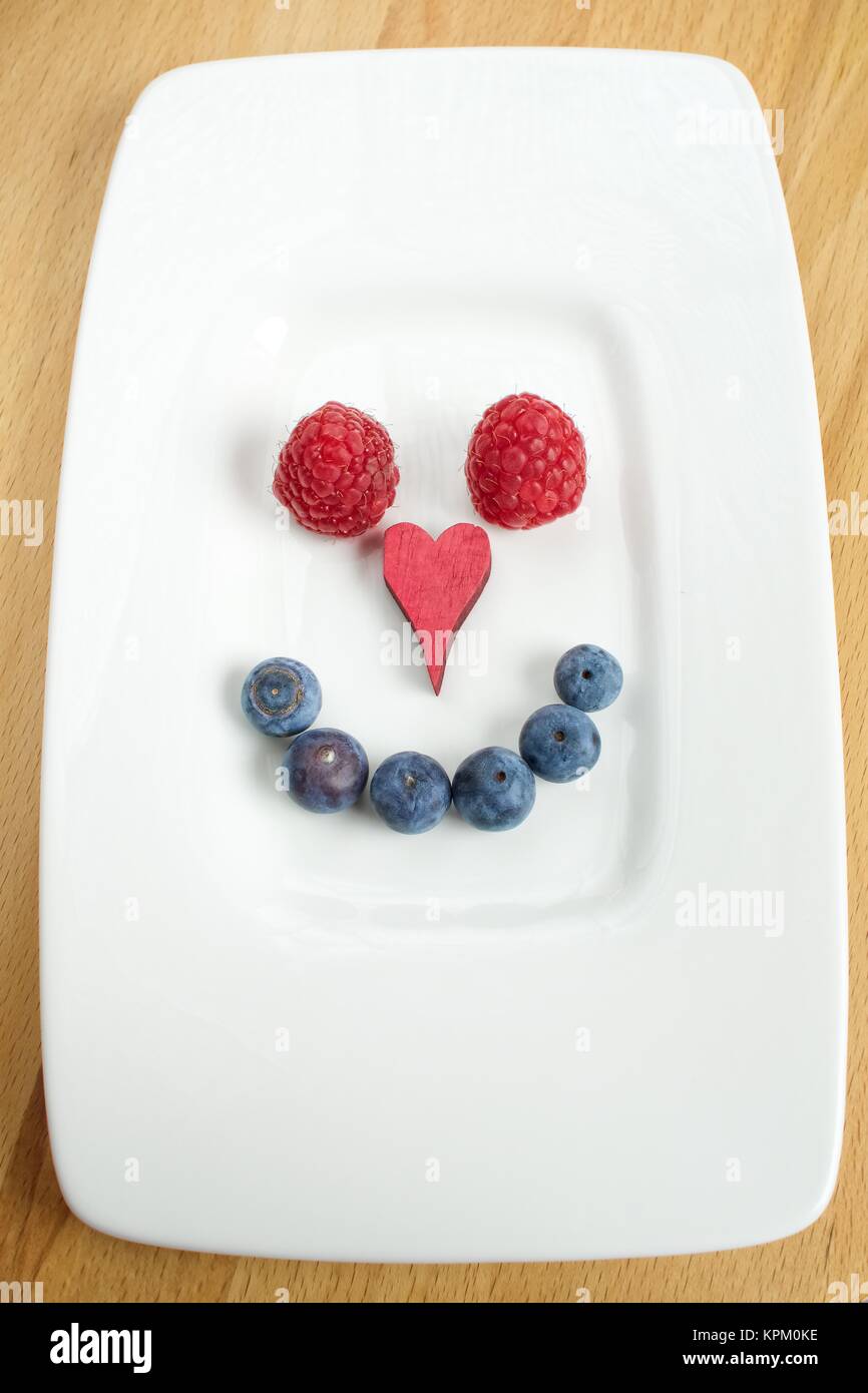 a smiling face made with raspberries and blueberries Stock Photo - Alamy