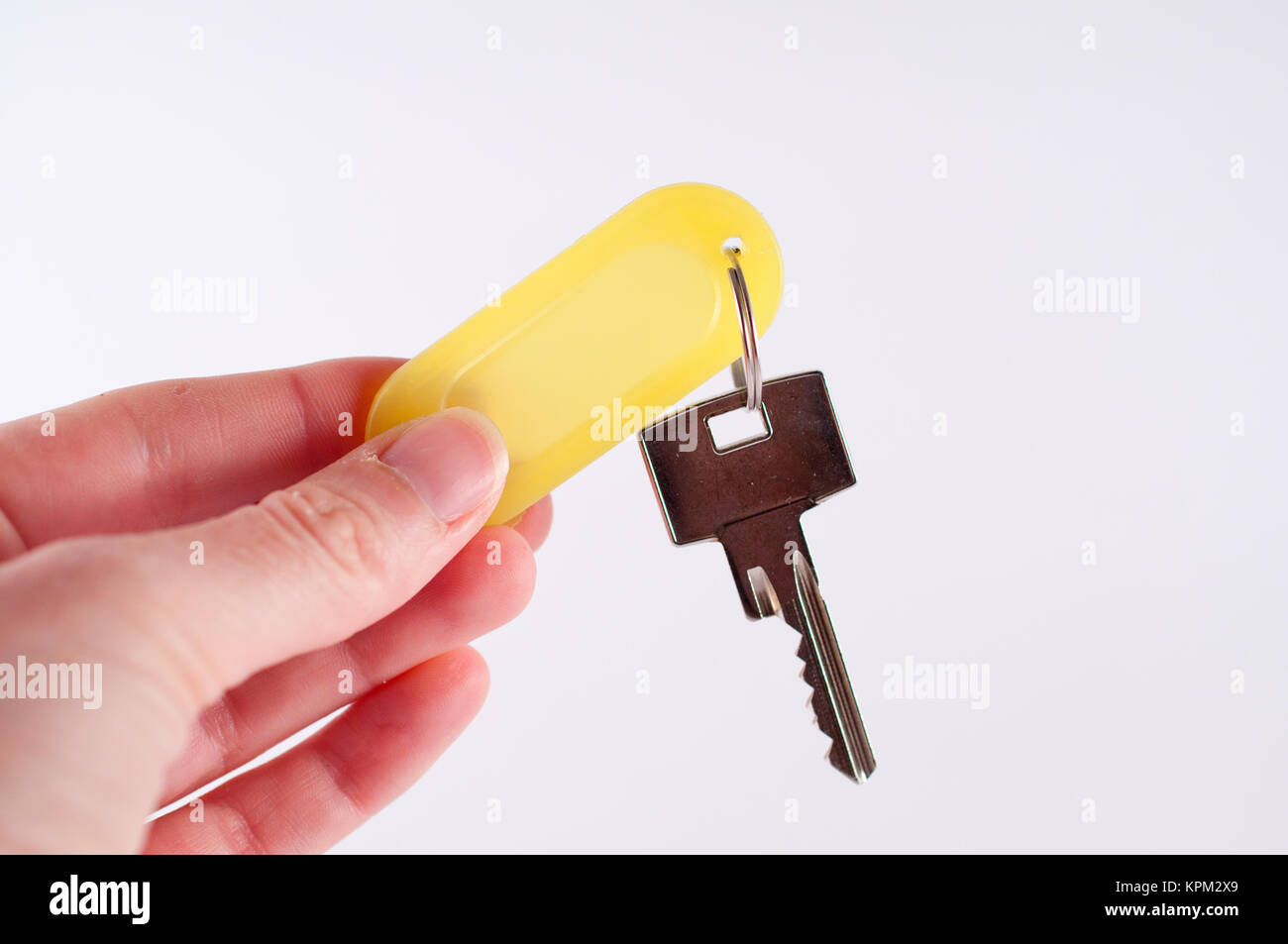 Hand holding metal key hanging on a yellow keyring Stock Photo - Alamy
