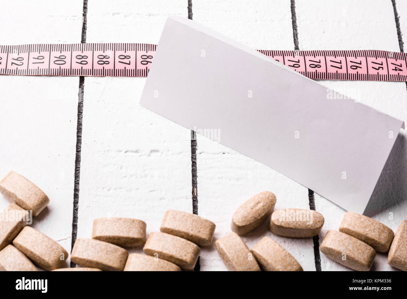 Pills, blank sheet of paper and pink measuring tape over the white ...