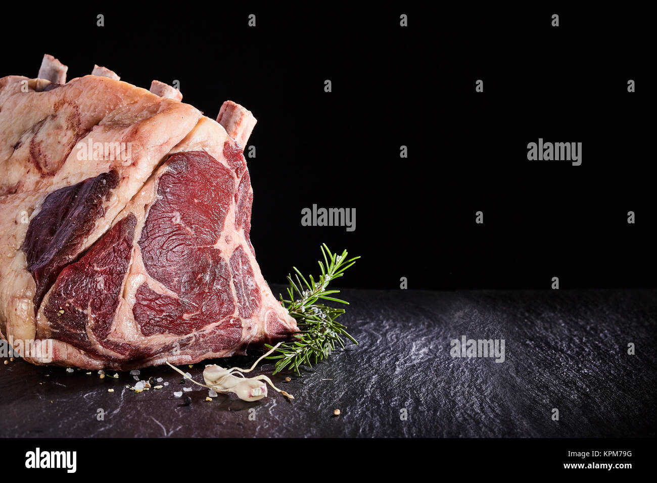 Single piece of raw uncooked beef ribs with garlic and rosemary over ...