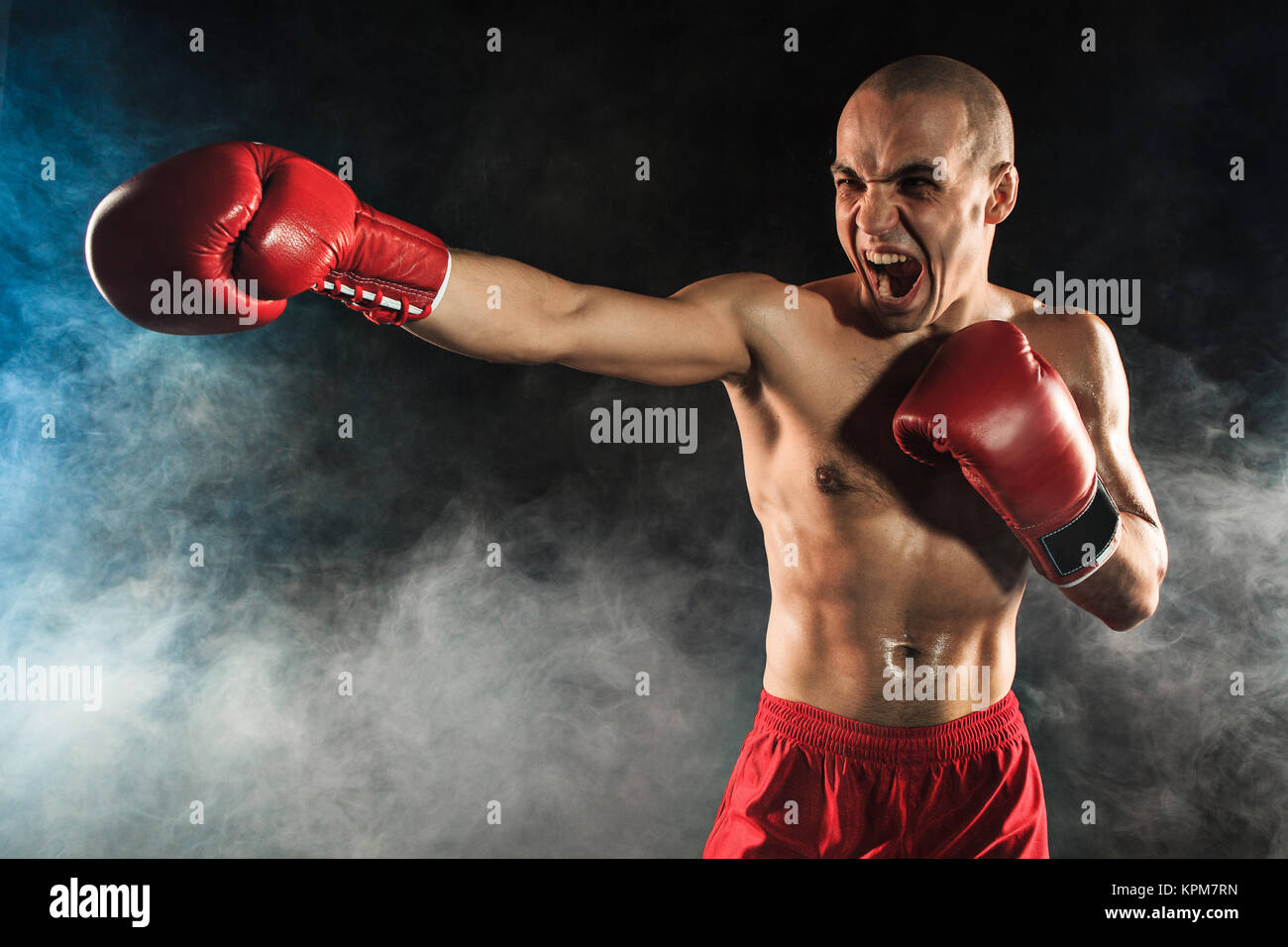 The young man kickboxing in blue smoke Stock Photo - Alamy