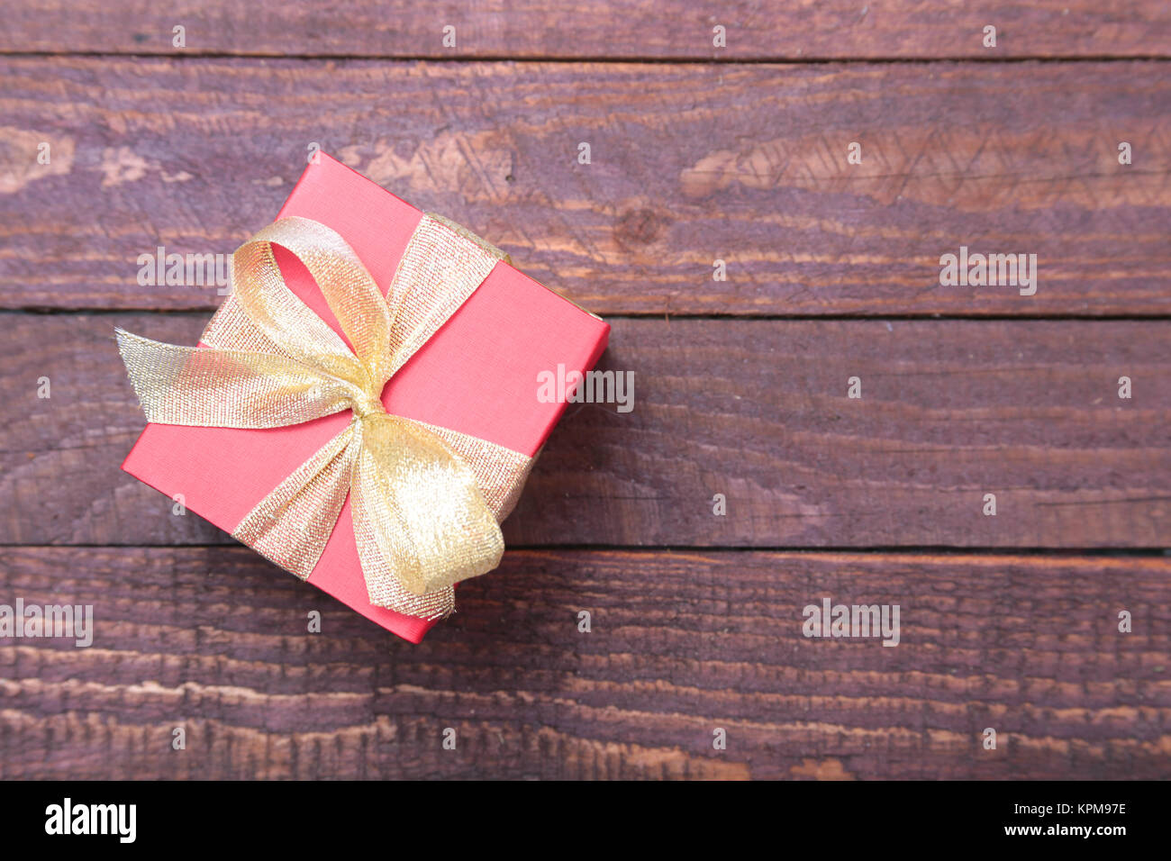 red and gold gift box on wood background Stock Photo - Alamy