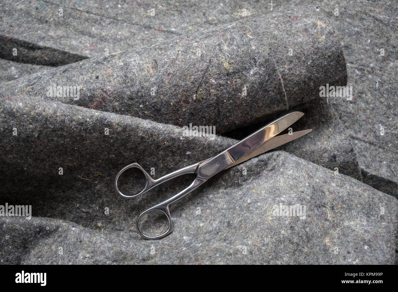 Grey geotextile fabric rolls with scissors on top. Tailoring, sewing ...