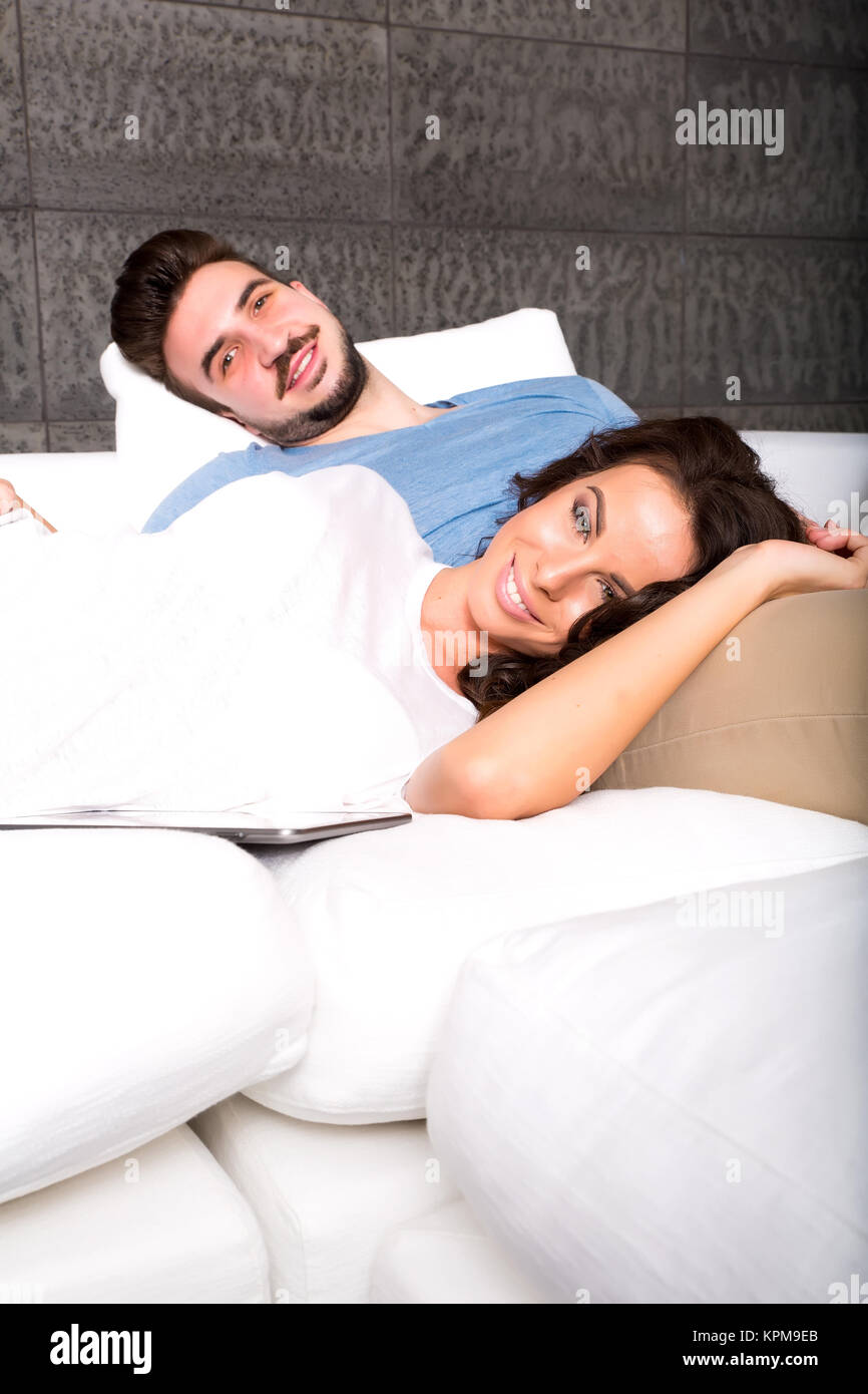 Young couple cuddling on the sofa at home Stock Photo - Alamy