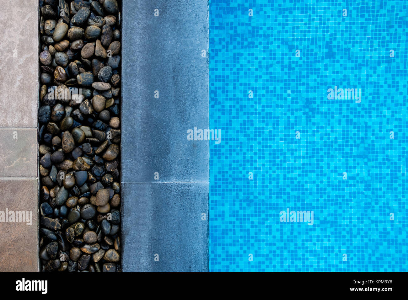 Edge of swimming pool with blue mosaic tiles at the bottom of the pool ...