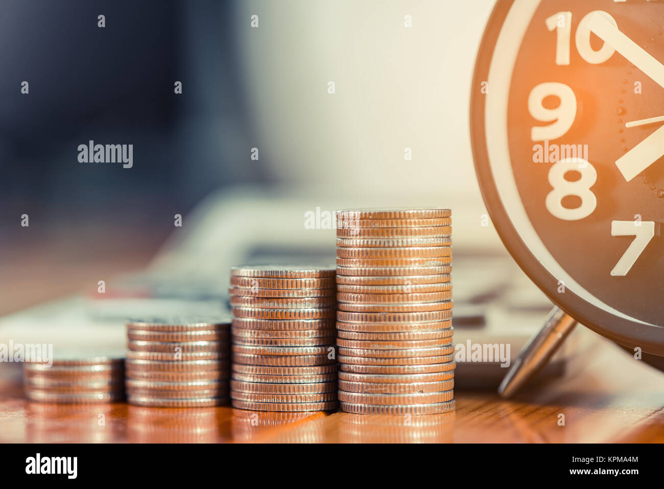 Alarm clock and step of coins stacks on working table, time for savings ...