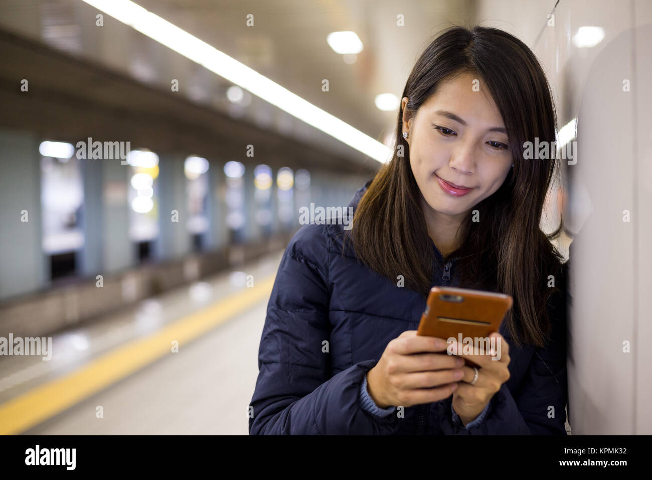 Woman use of mobile phone in train platform Stock Photo - Alamy