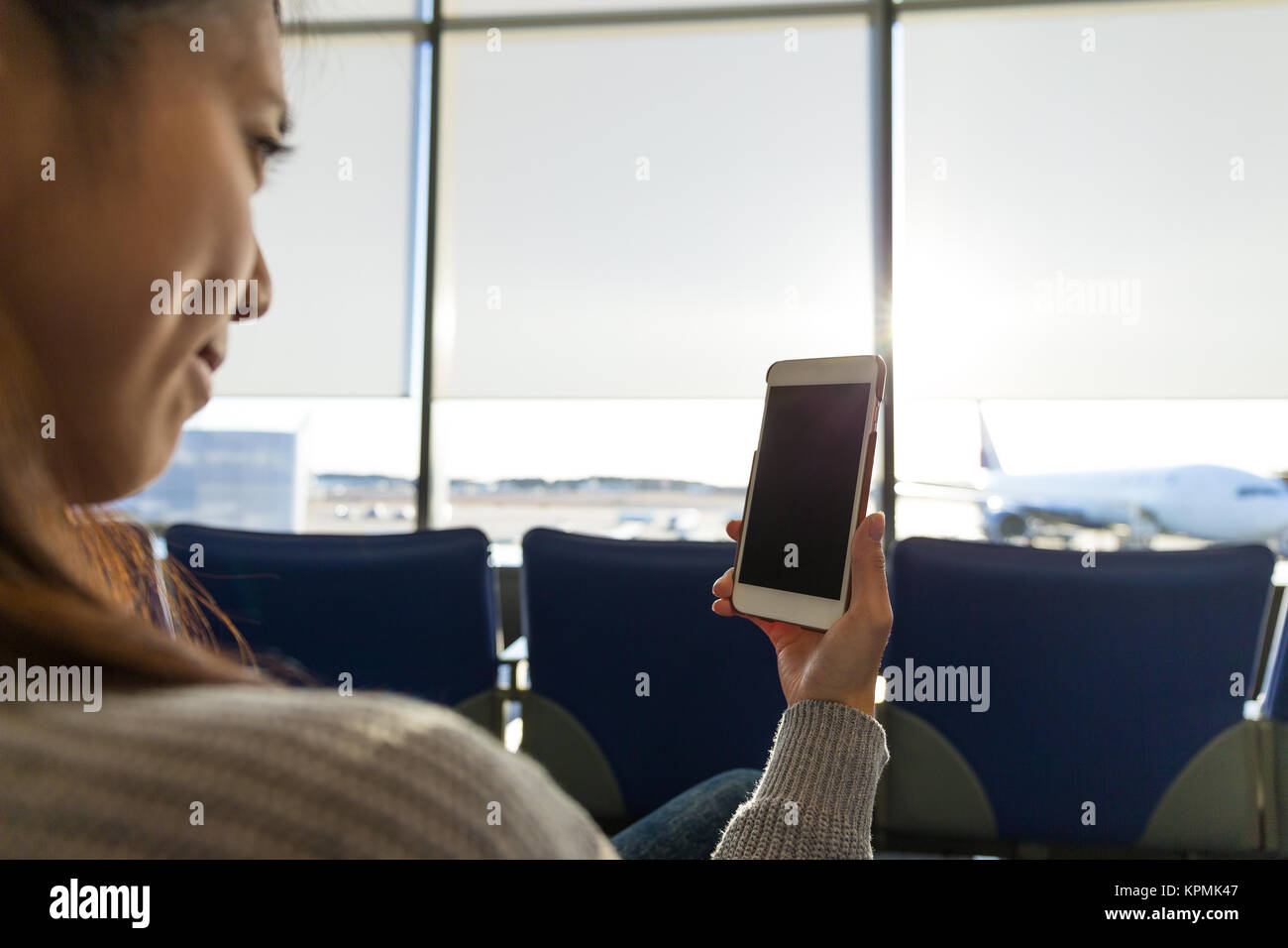Woman use of cellphone in airport Stock Photo - Alamy