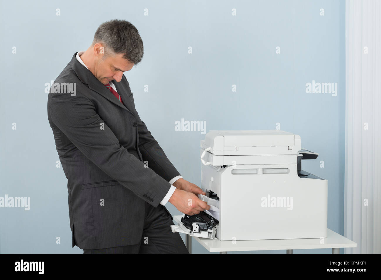 Businessman Removing Paper Stuck In Printer At Office Stock Photo - Alamy