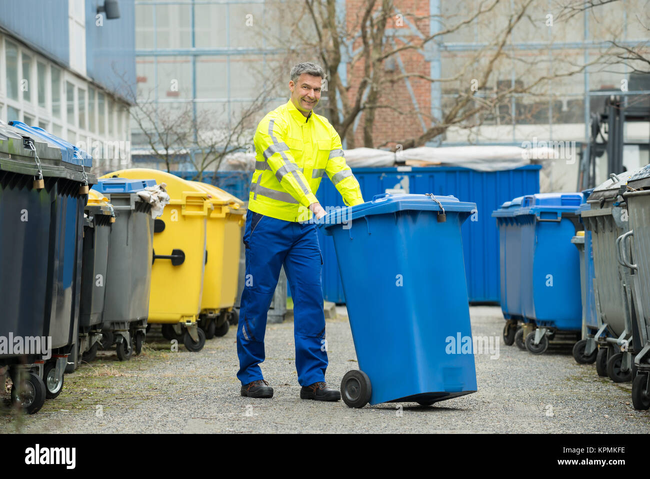 Male Worker Walking With Dustbin On Street Stock Photo - Alamy
