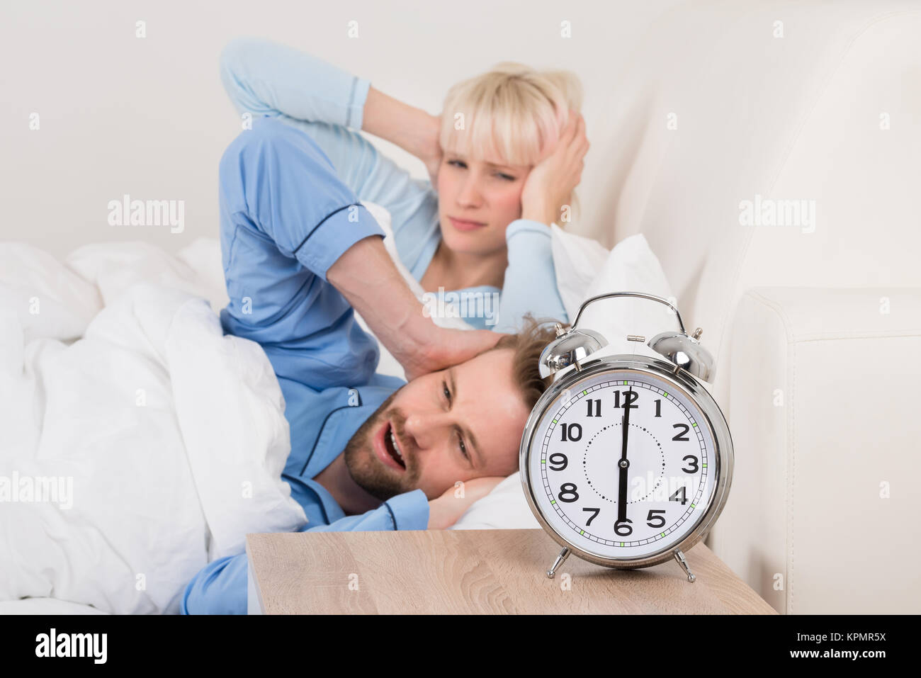 Young Couple Awakened By Alarm Clock Stock Photo - Alamy