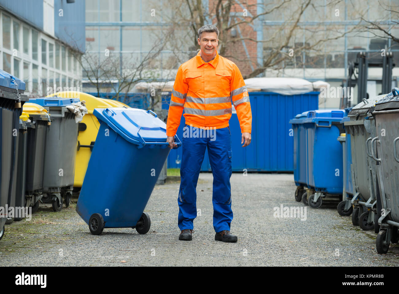 Male Worker Walking With Dustbin On Street Stock Photo - Alamy