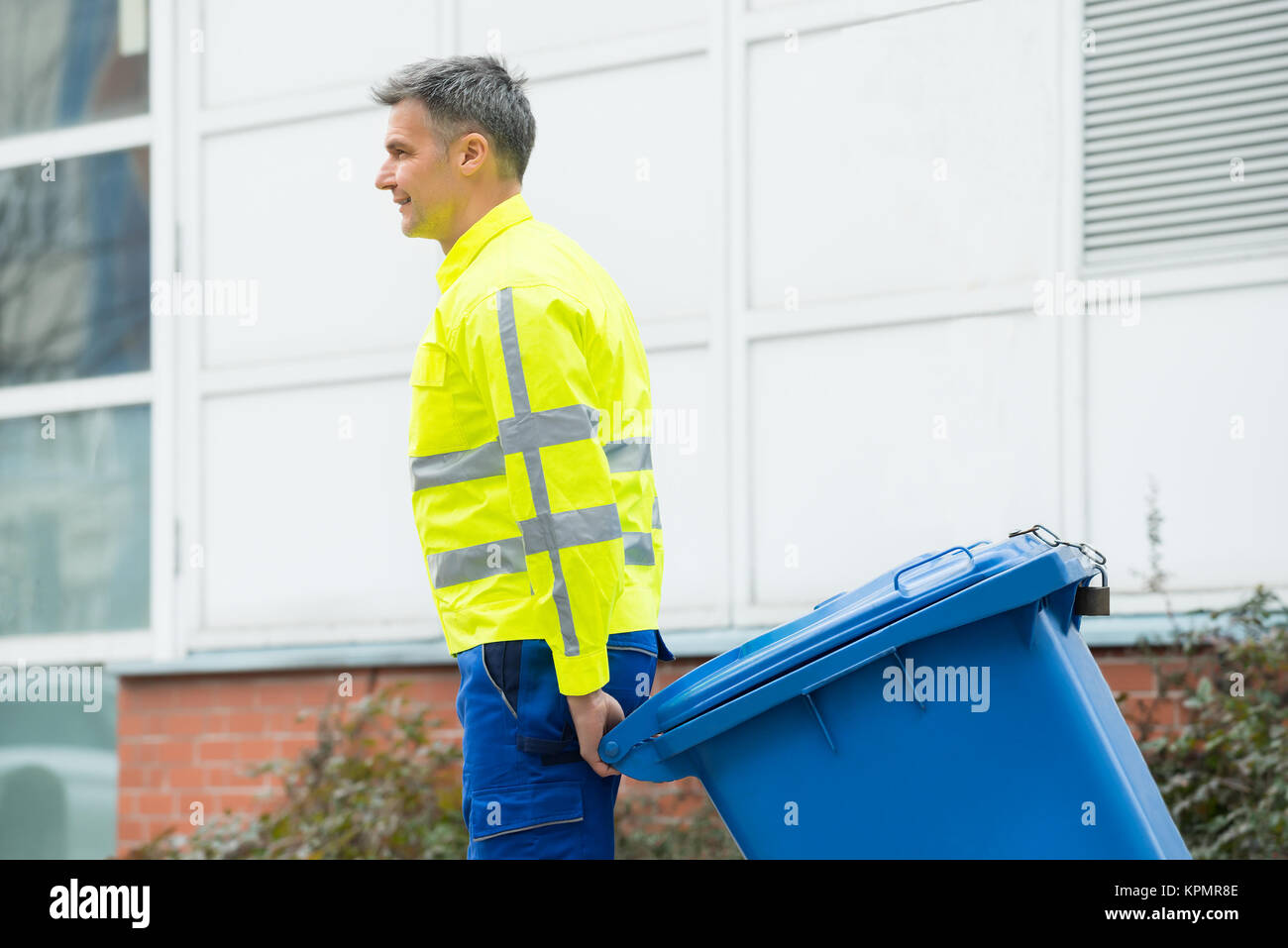 Male Worker Walking With Dustbin On Street Stock Photo - Alamy