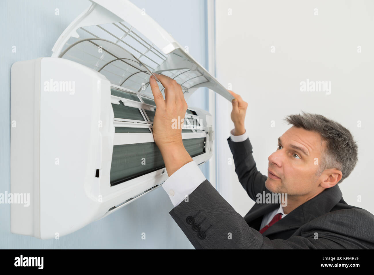 Businessman Checking Air Conditioner Mounted On Wall In Office Stock ...