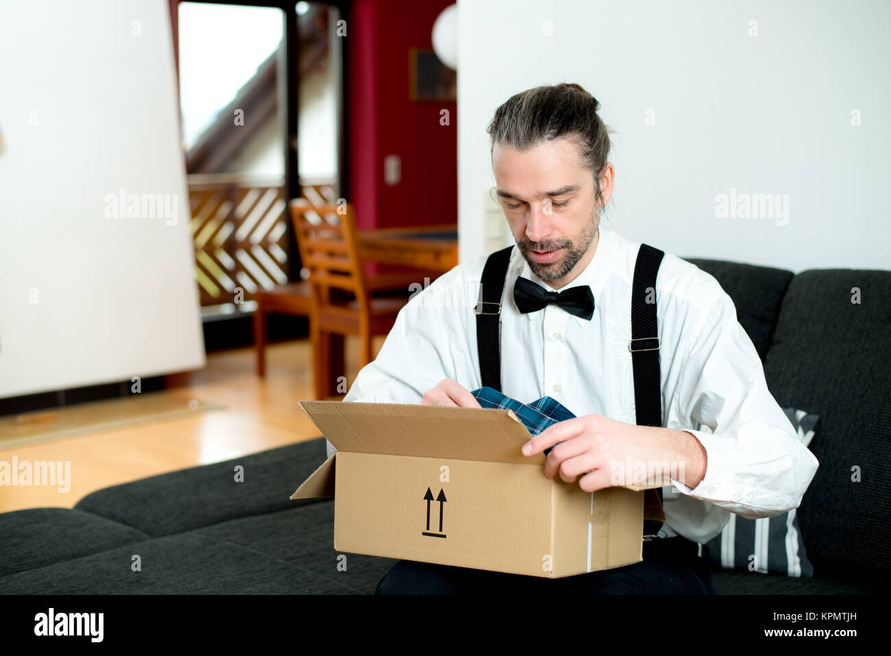 young bearded man in white shirt with bow-tie opening a package Stock ...