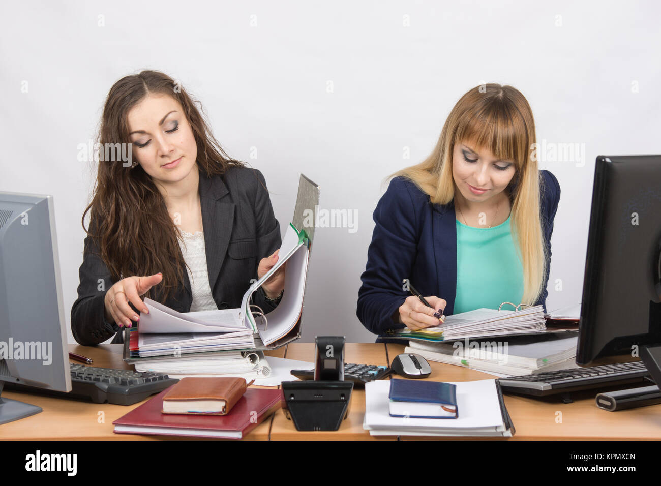 Two office employee sitting at a desk and working with papers and ...