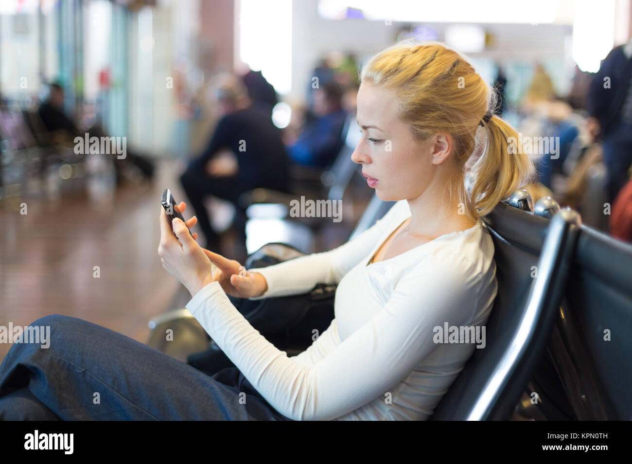 Female traveler using cell phone while waiting Stock Photo - Alamy
