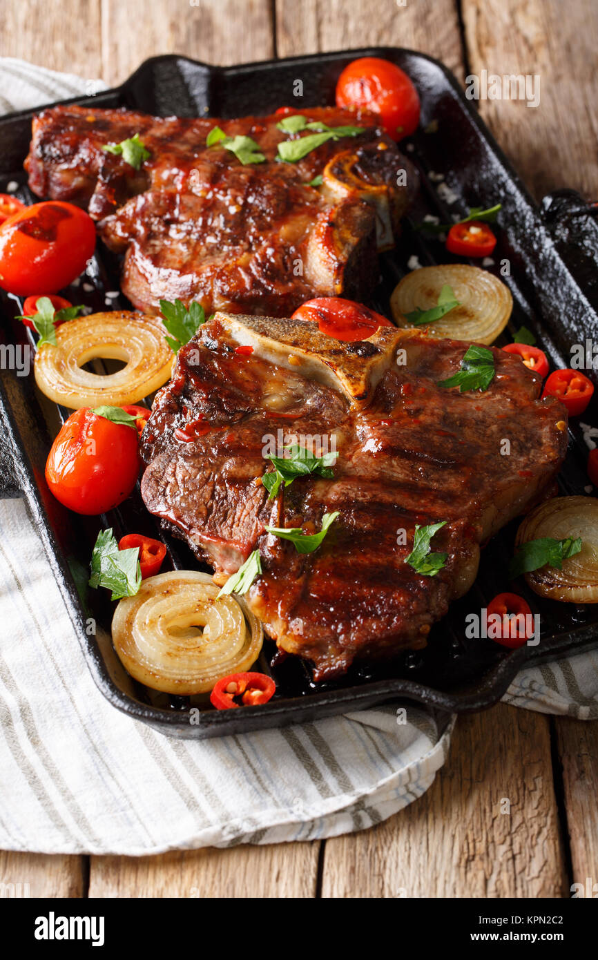 Spicy hot T Bone Steak with tomato, chili and onion in a grill pan ...
