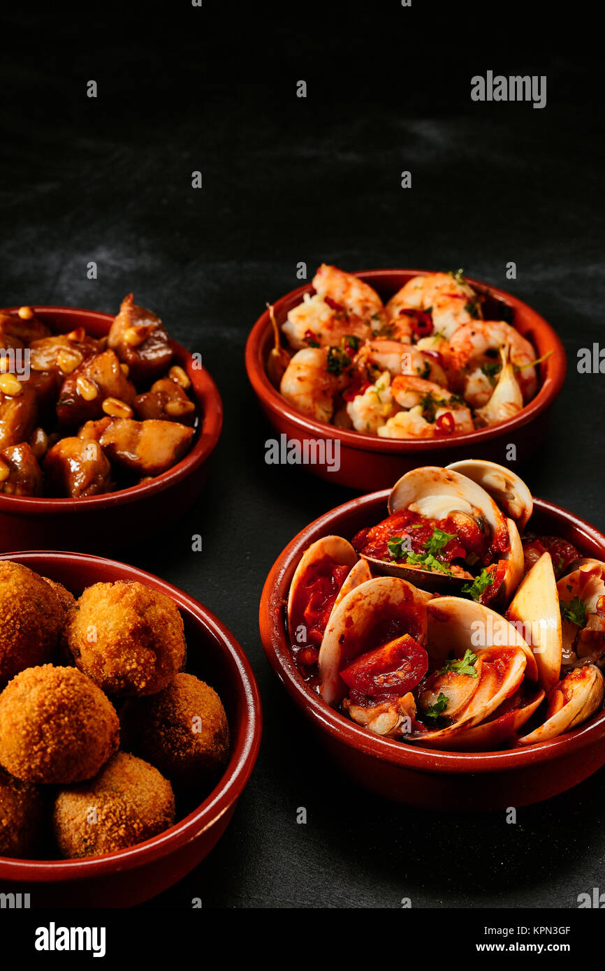 Four round ceramic bowls of delicious traditional Spanish tapas on ...