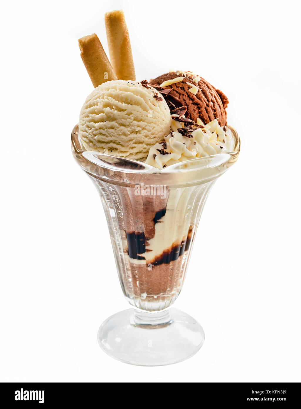 Chocolate and vanilla ice cream sundae in a tall glass topped with nut ...