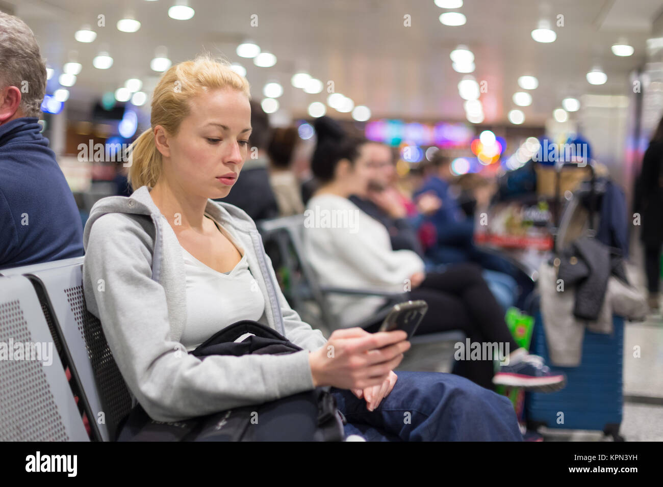 Female traveler using cell phone while waiting Stock Photo - Alamy
