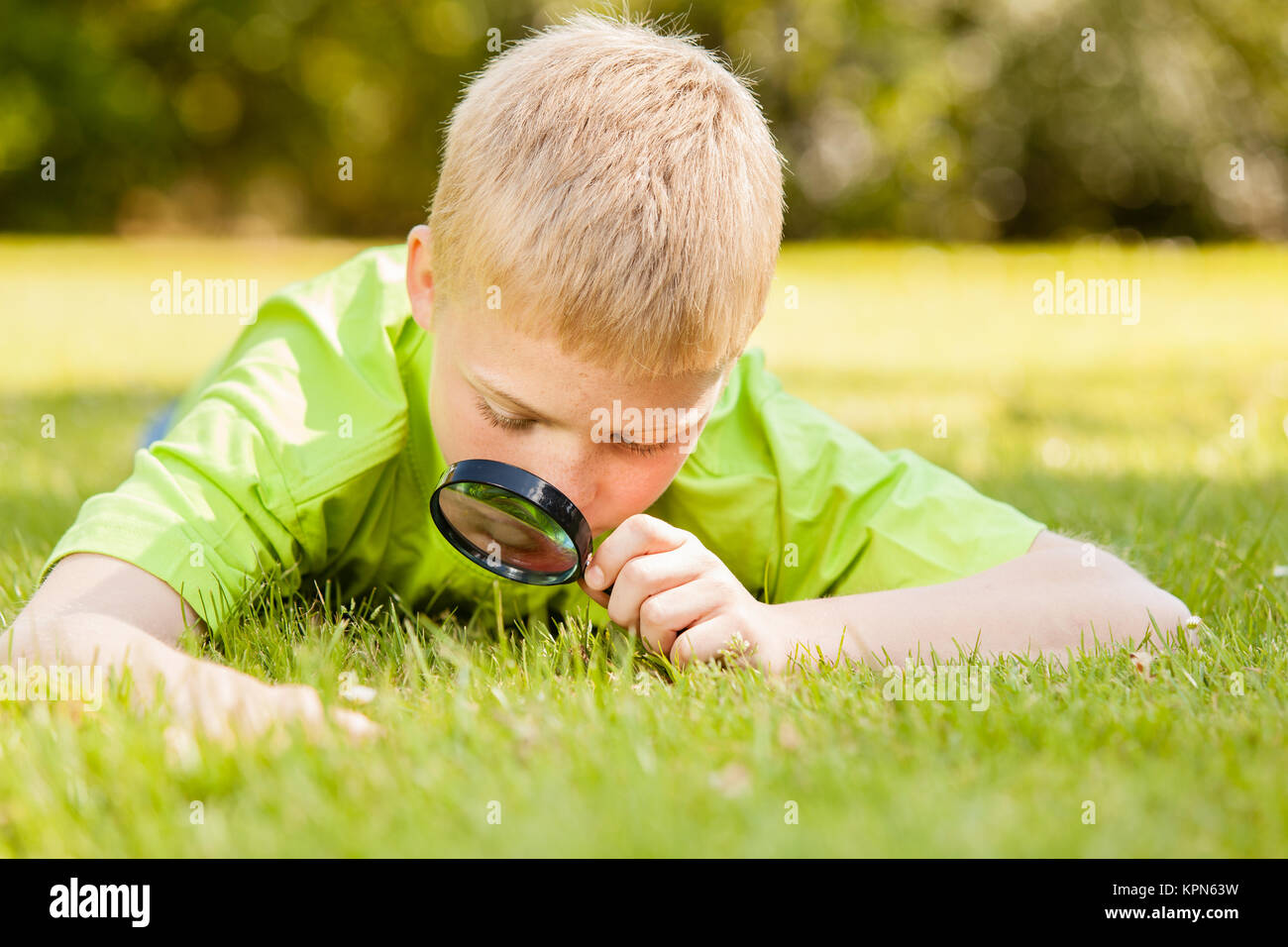 Child looking through magnifying glass on ground Stock Photo - Alamy