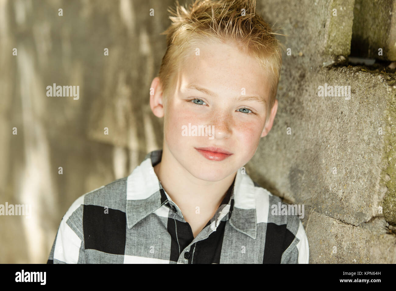Grinning handsome boy near stone wall Stock Photo - Alamy