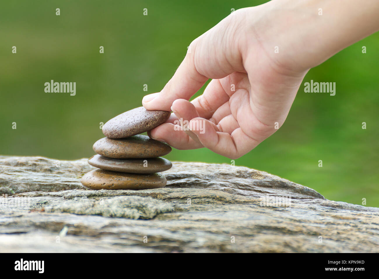 Hand put stone building a pile of zen stones Stock Photo - Alamy