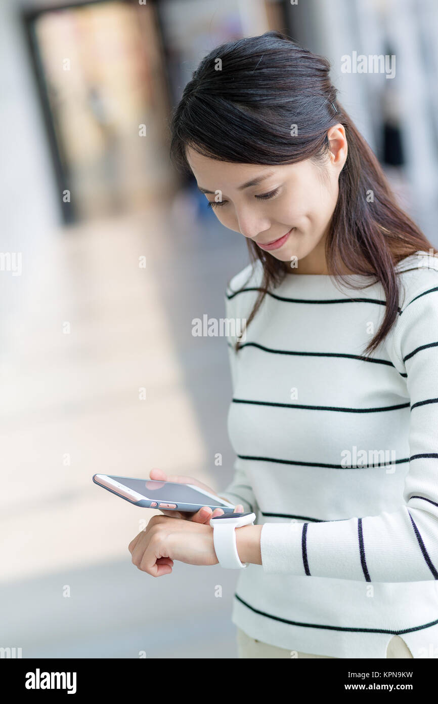 Woman connecting the cellphone with smart watch Stock Photo - Alamy