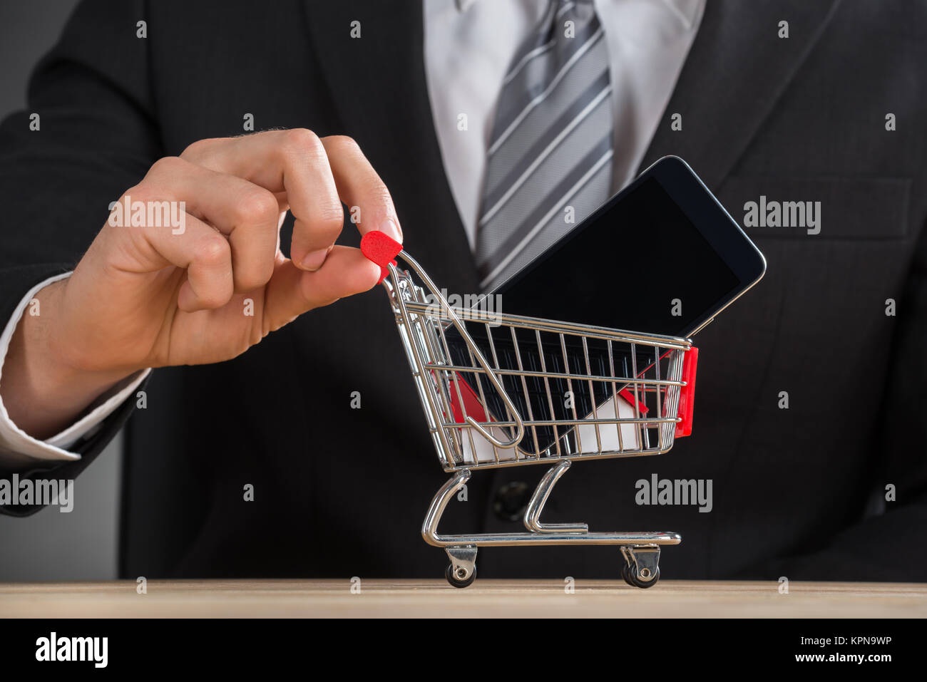 Businessman Holding Shopping Trolley With Mobile Phone Stock Photo - Alamy