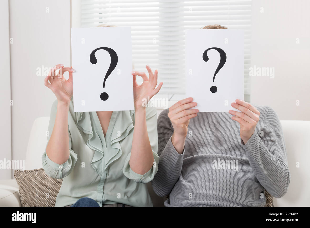 Couple Holding Question Mark Sign In Front Of Face Stock Photo - Alamy