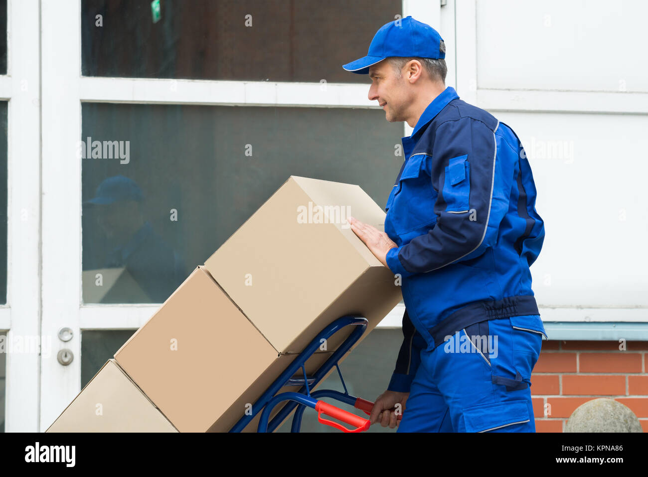 Delivery Man Carrying Boxes On A Hand Truck Stock Photo - Alamy