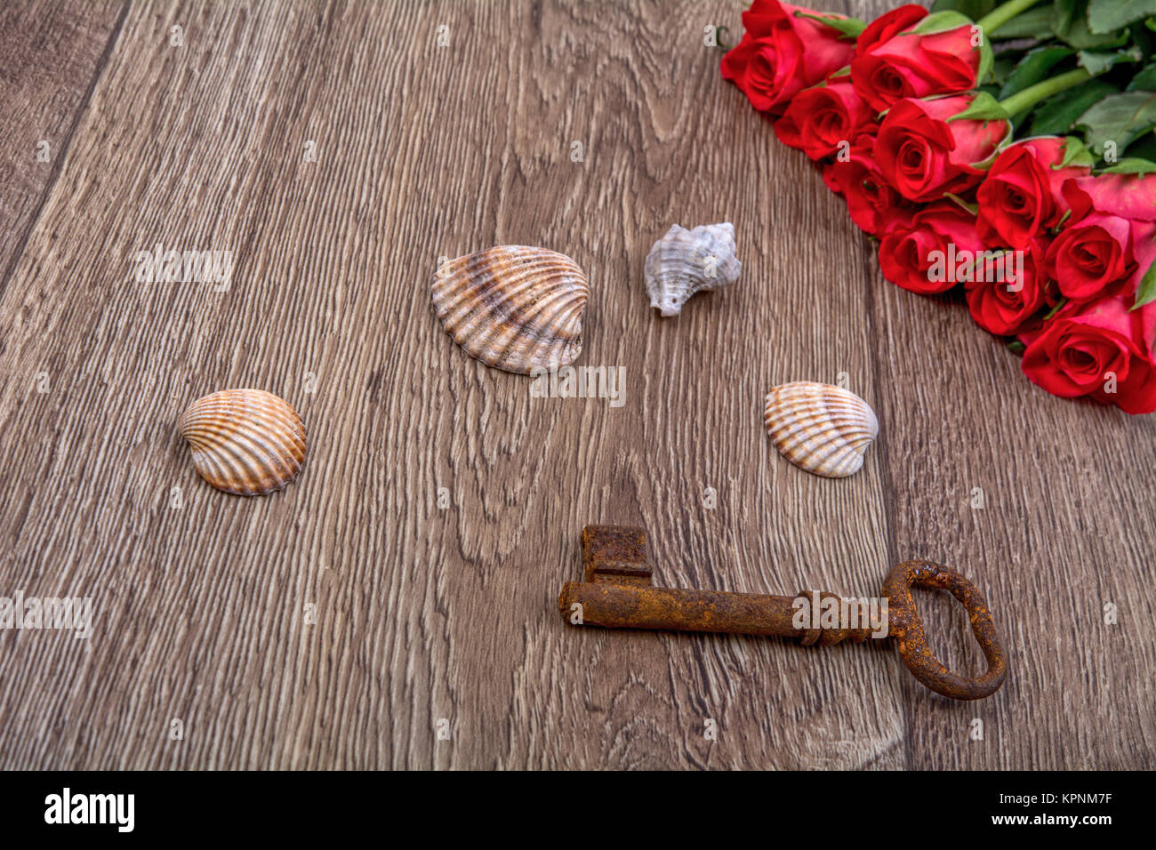 Rusty key, sea shell and roses on a wooden background Stock Photo - Alamy