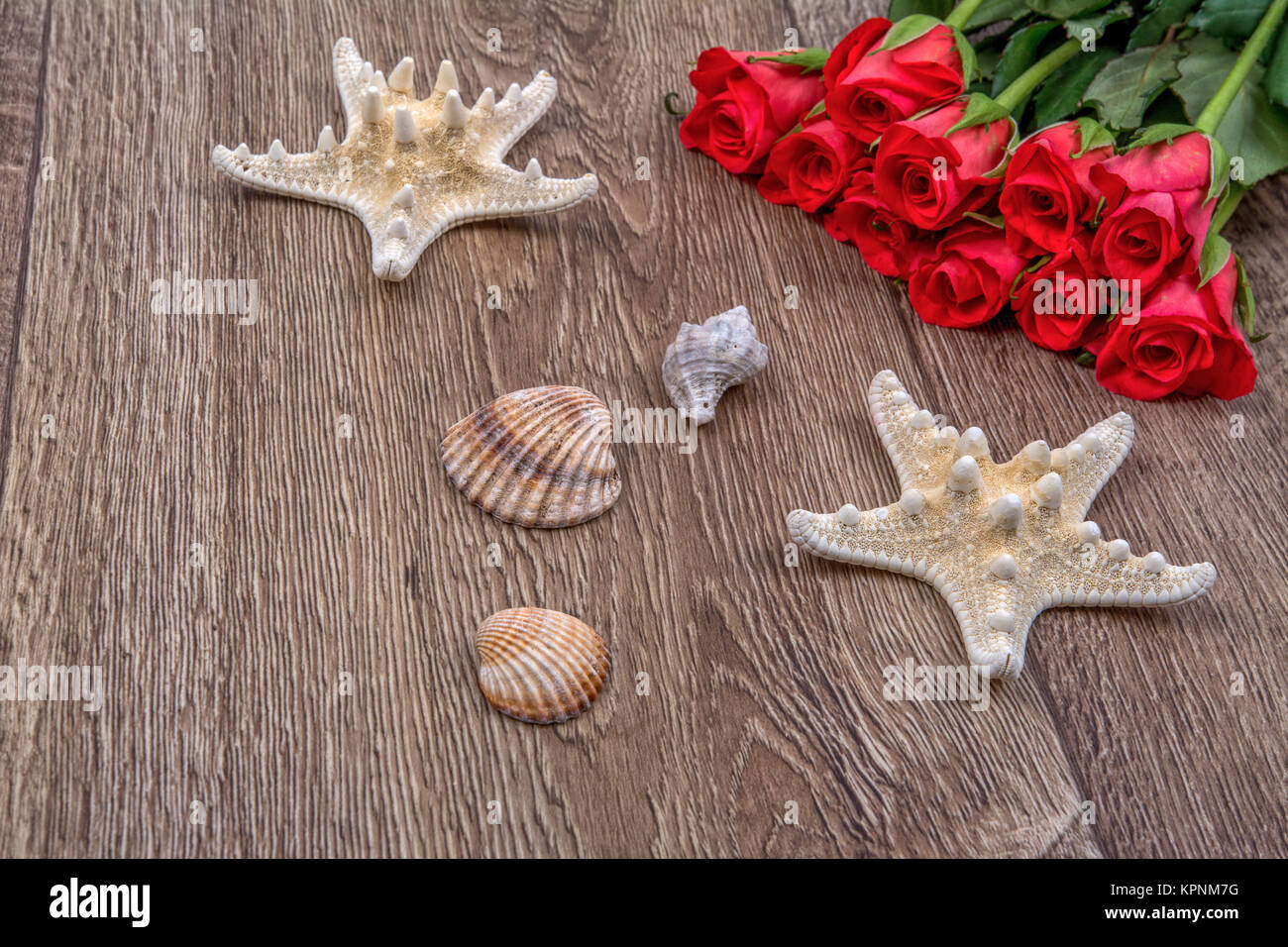 Starfishes, shells and red roses on a wooden background Stock Photo - Alamy