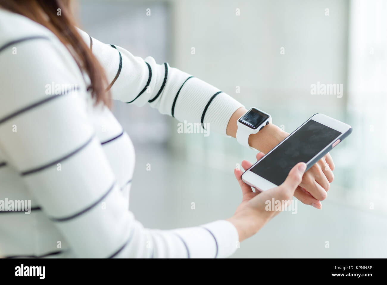 Woman connecting smartwatch and cellphone Stock Photo - Alamy