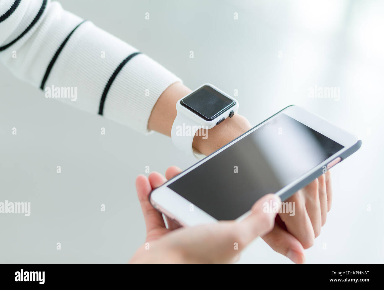 Woman using cellphone to connect with smart watch Stock Photo - Alamy