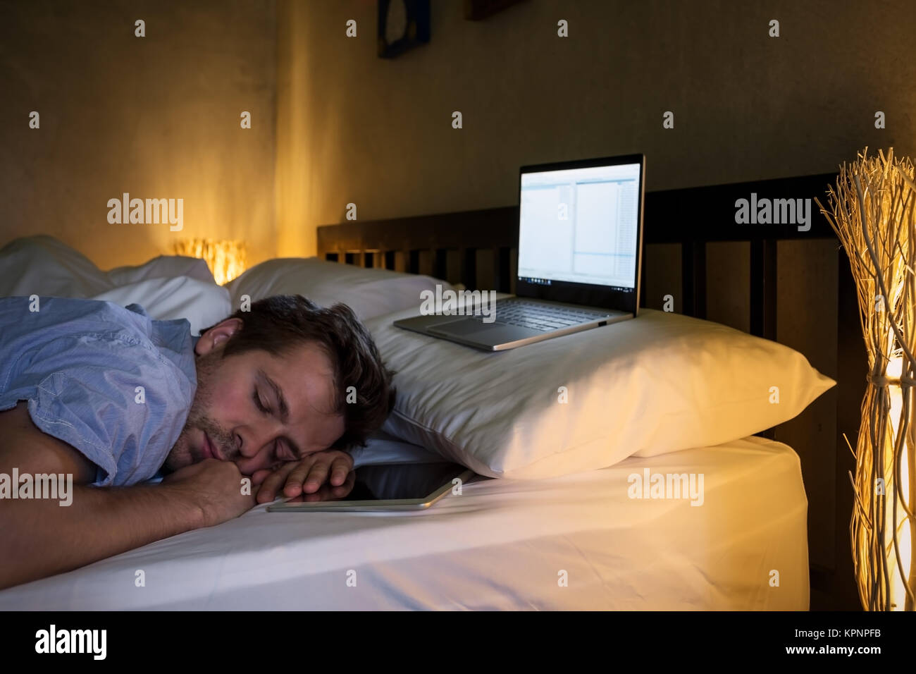 Portrait of young caucasian tired man laying on bed using laptop for a ...