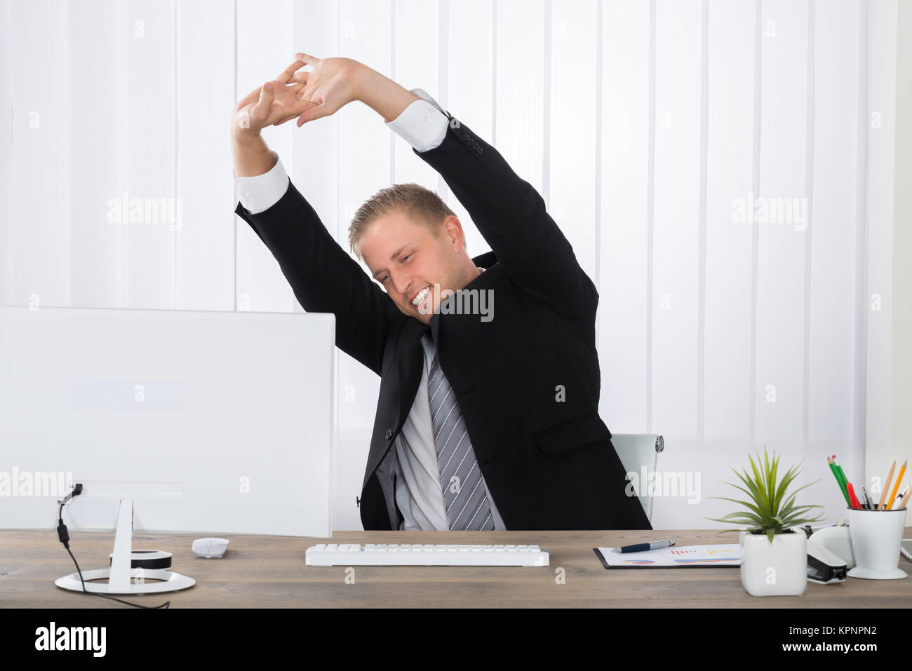 Businessman Stretching In Office Stock Photo - Alamy