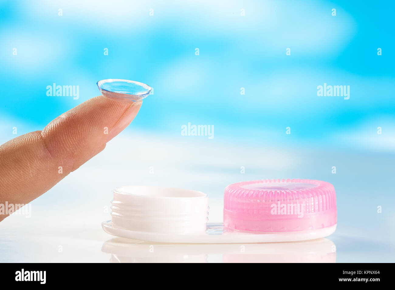 Contact lens on finger tip blue background Stock Photo - Alamy